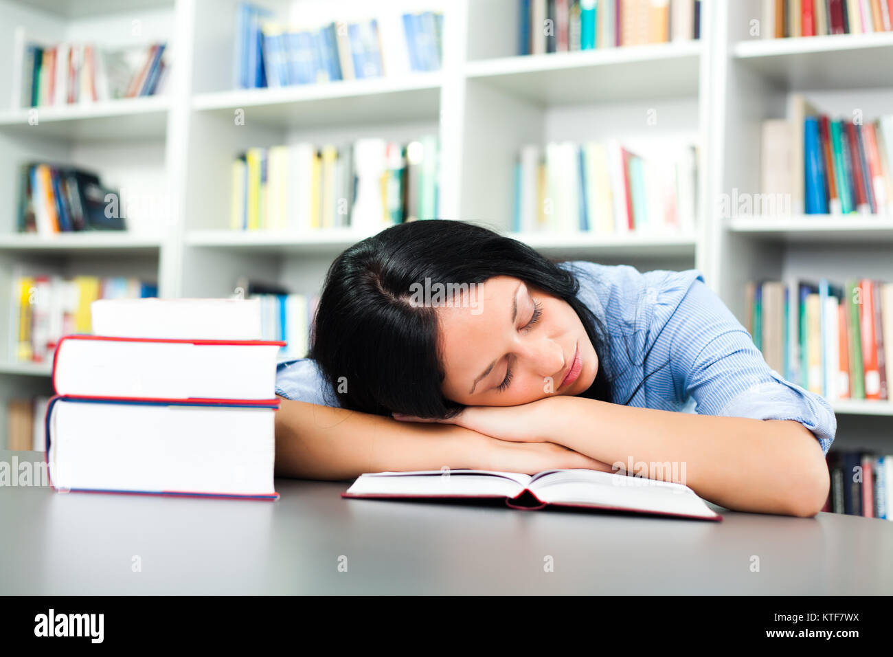 Tired student sleeping in library Stock Photo - Alamy