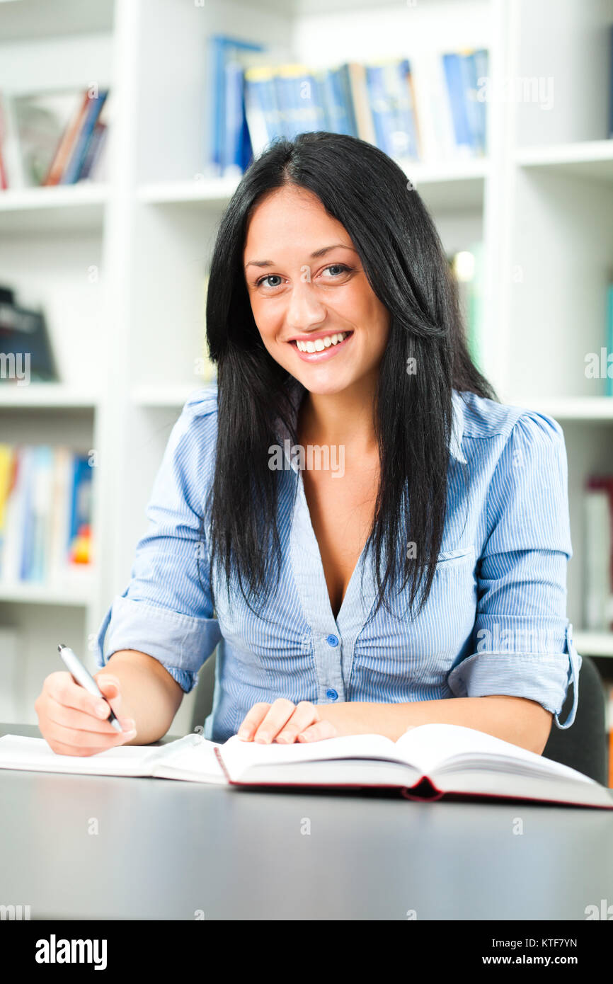 Happy student learning in library Stock Photo - Alamy