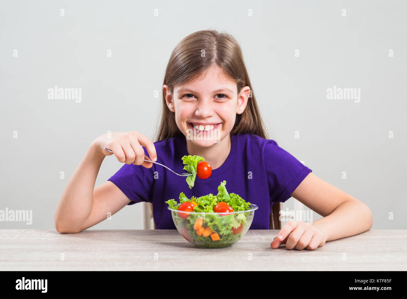Happy little girl is eating salad Stock Photo - Alamy