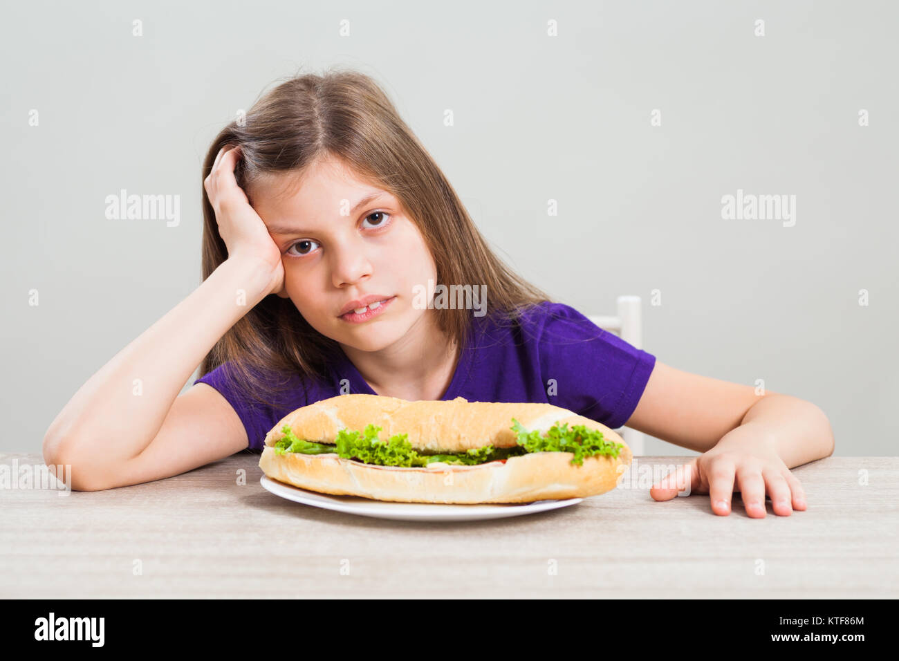Little girl is unhappy because she has to eat sandwich for breakfast ...