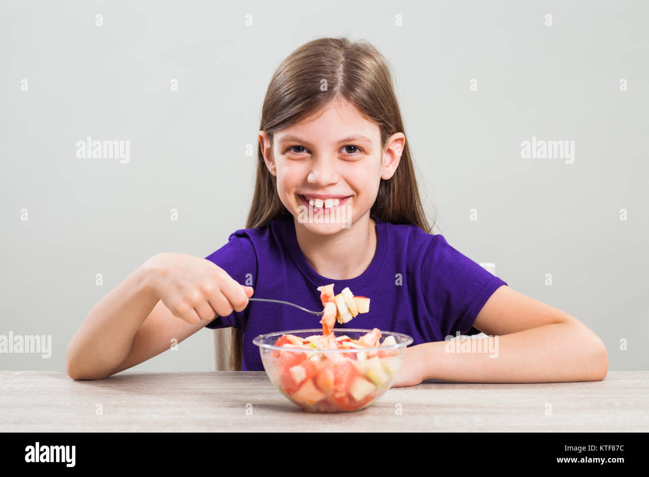 Happy little girl is eating fruit salad Stock Photo - Alamy