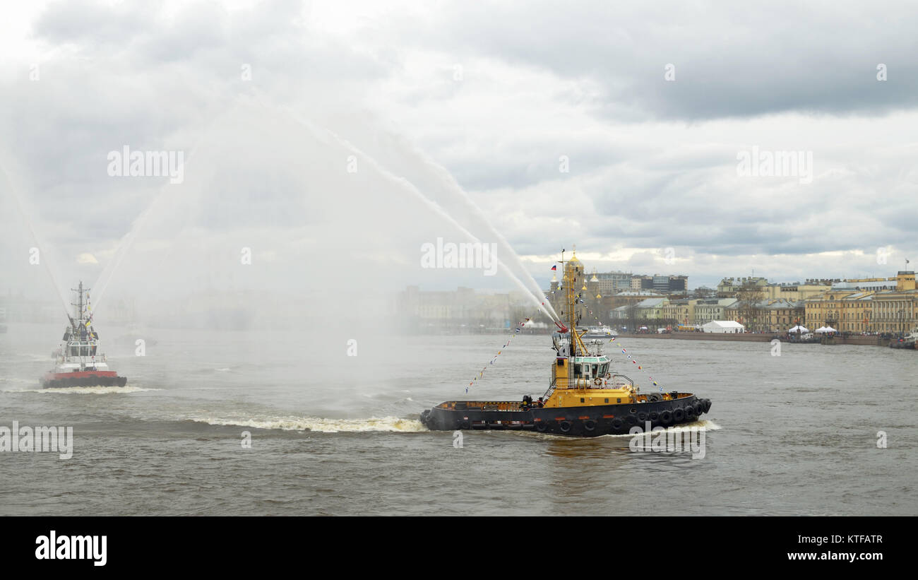 Marine boat tug boat floats on the river and throws up water fountains ...