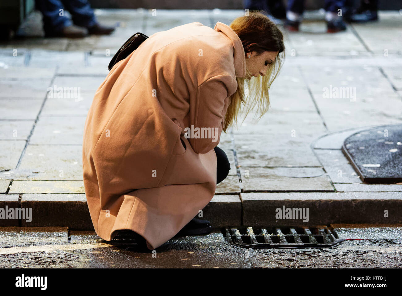 A woman crouches down on the road in Wind Street, Swansea, Wales on Mad ...