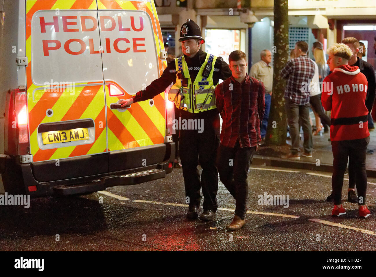 Police officers detain a man in Wind Street, Swansea, Wales on Mad ...