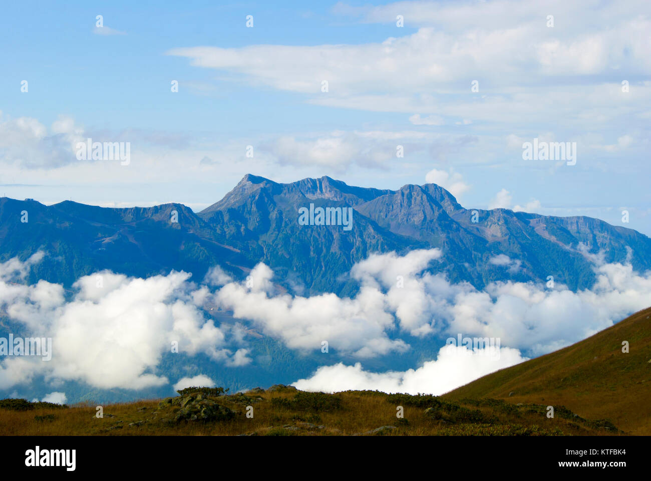 mountain landscape with a blue ridge and clouds in the valley deep down ...
