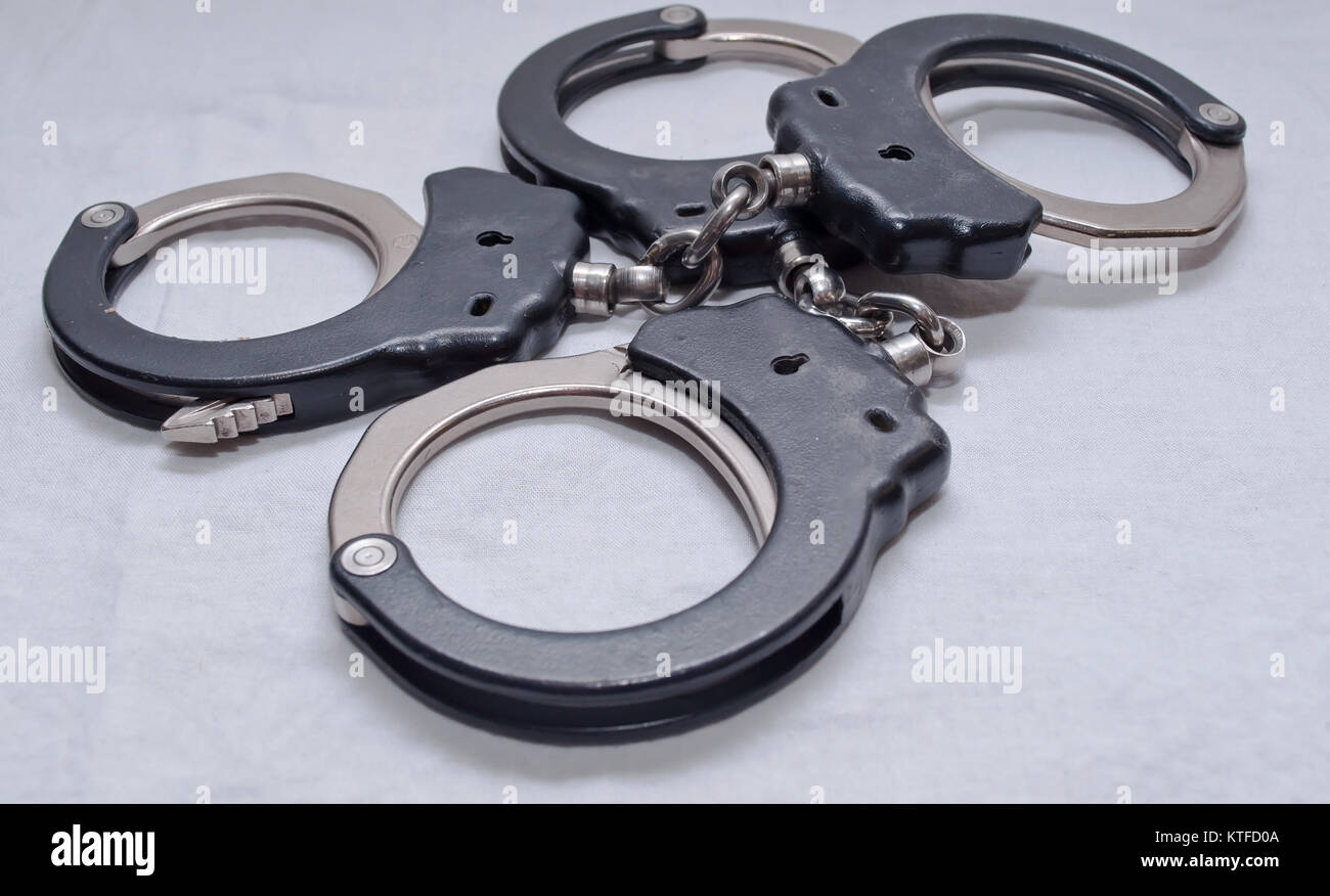 Two pair of handcuffs together on a white background Stock Photo - Alamy