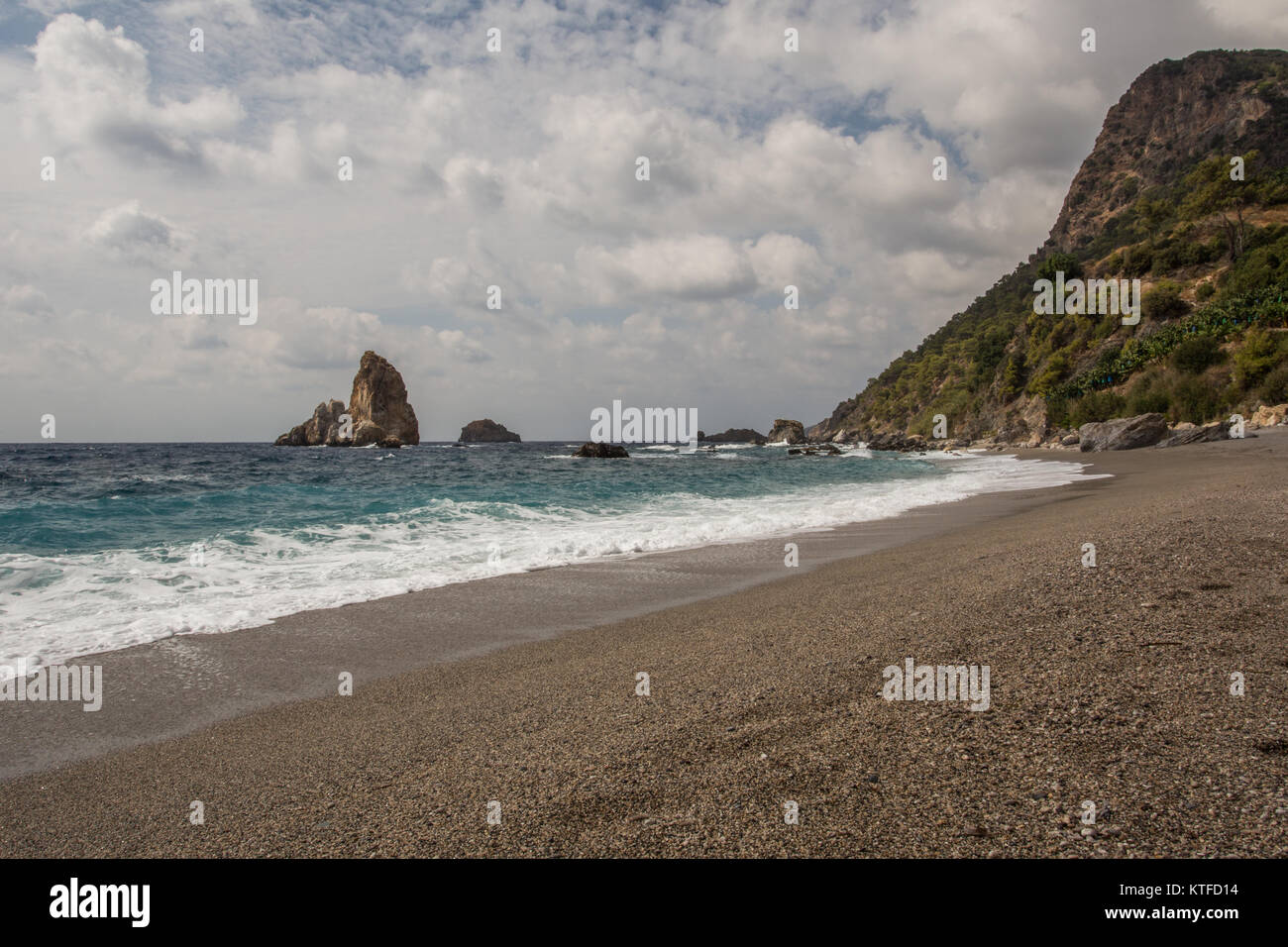 Seascape with small pebble beach, rocks in the sea and mountain ...