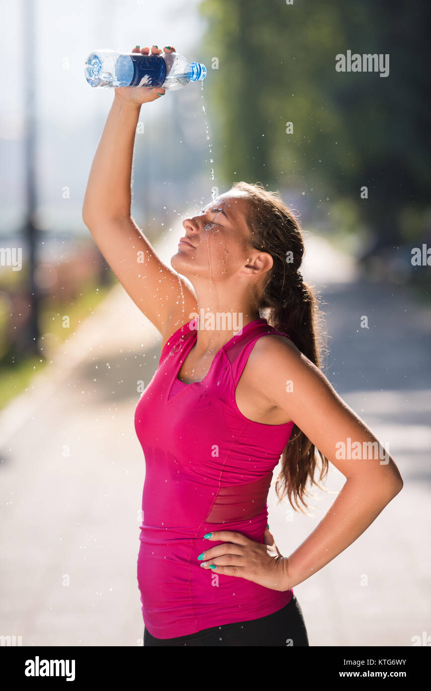 Athlete woman runner pouring water from bottle on her head after ...