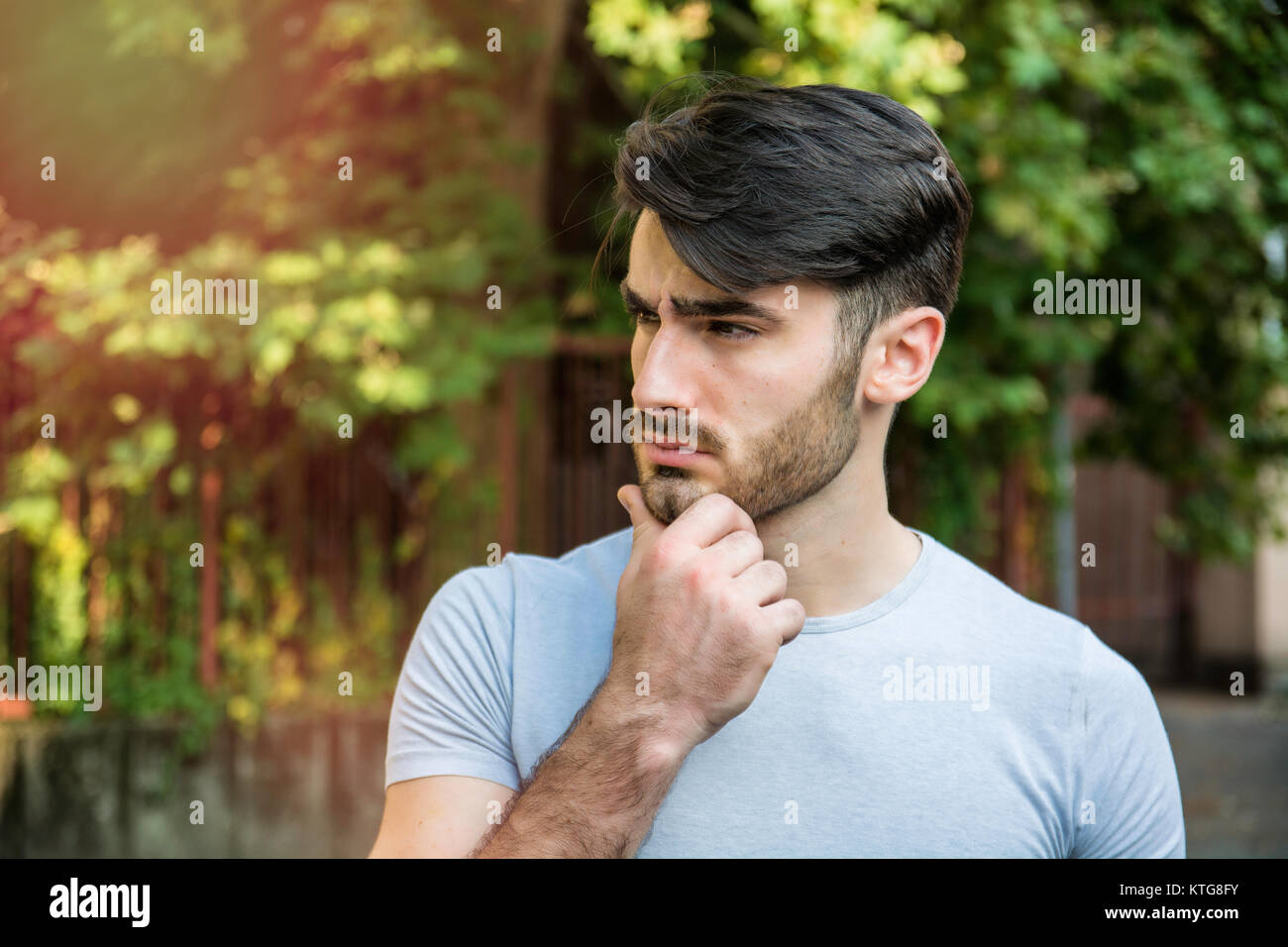Confused or doubtful young man scratching his head and looking up ...