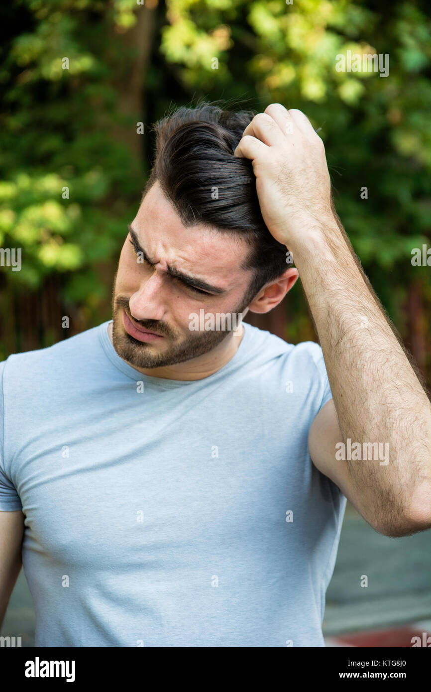Confused Or Doubtful Young Man Scratching His Head And Looking Down