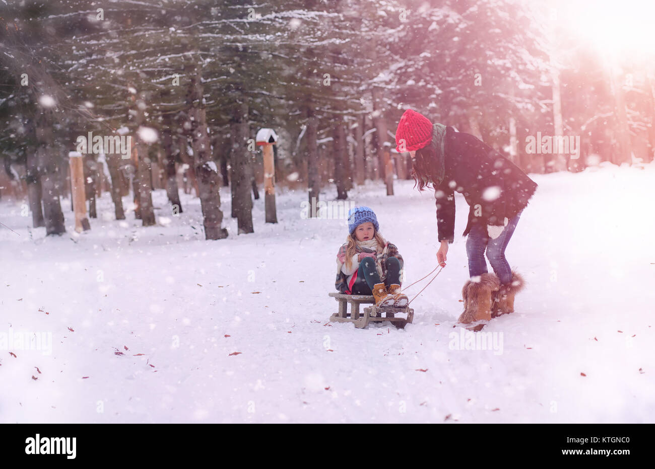 Winter fairy tale, a young mother and her daughter ride a sled in the ...