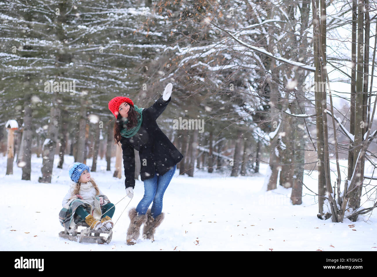 Winter fairy tale, a young mother and her daughter ride a sled in the ...