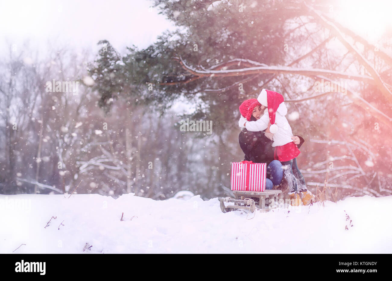 Winter fairy tale, a young mother and her daughter ride a sled in the ...