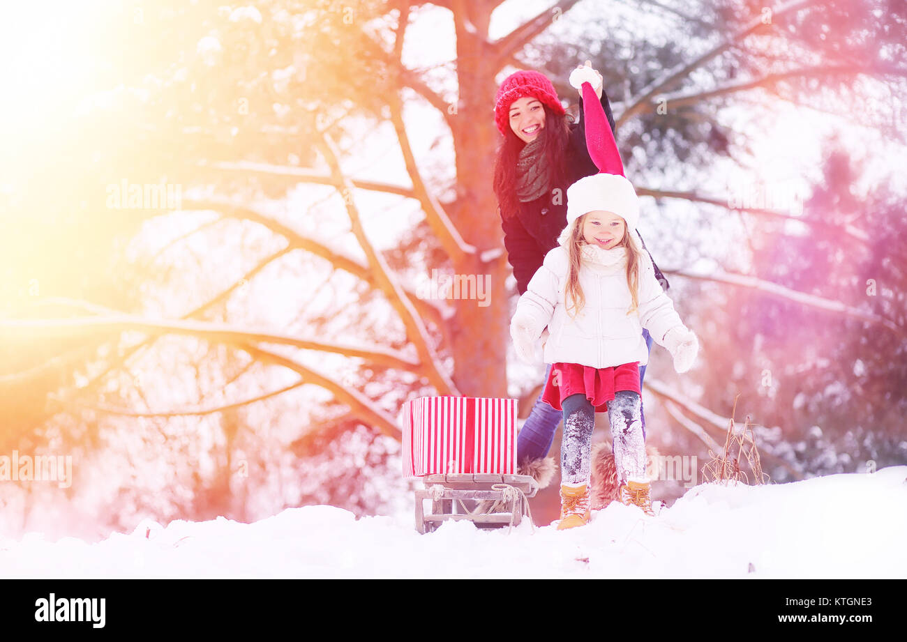 Winter fairy tale, a young mother and her daughter ride a sled in the ...