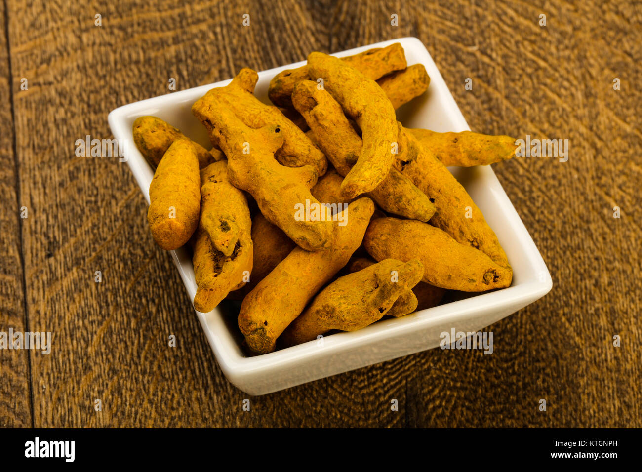 Tumeric roots heap in the bowl over wooden background Stock Photo - Alamy