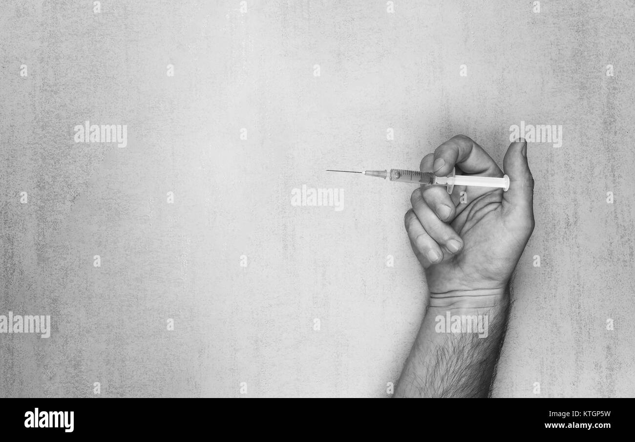 Male hand with disposable syringe for injection on a gray background ...