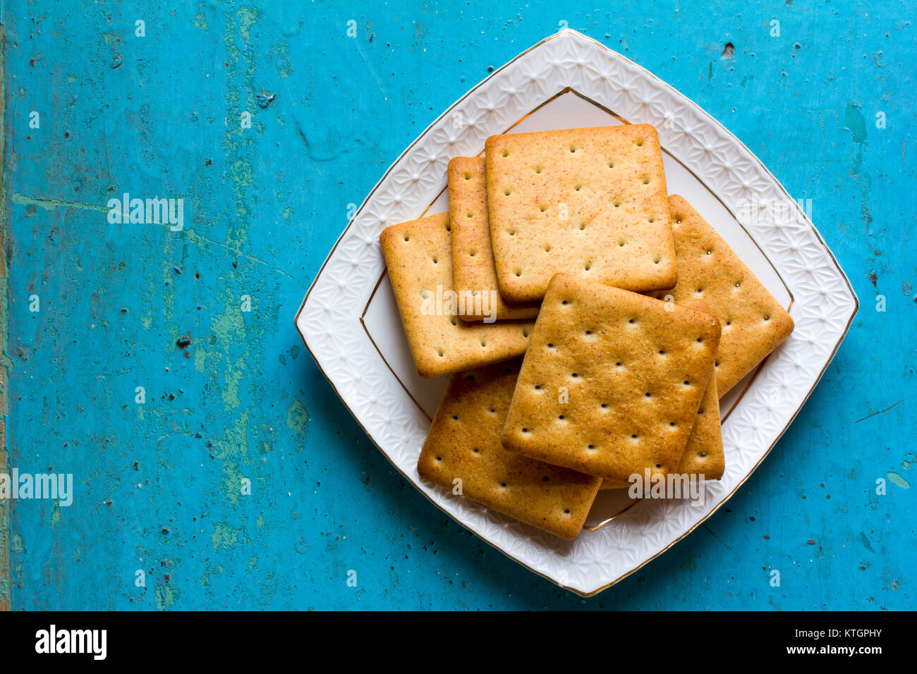 Cracker biscuits in a white ceramic square saucer on old blue ...