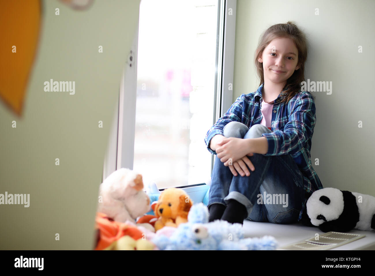 Child in the children's room. The kid is sitting on the windowsill at ...