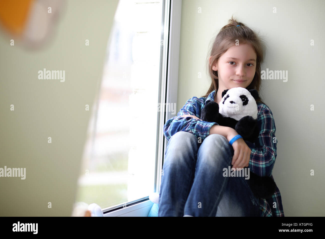 Child in the children's room. The kid is sitting on the windowsill at ...