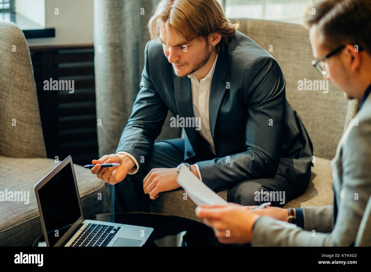 Two male employees consulting with laptop in cafe Stock Photo - Alamy
