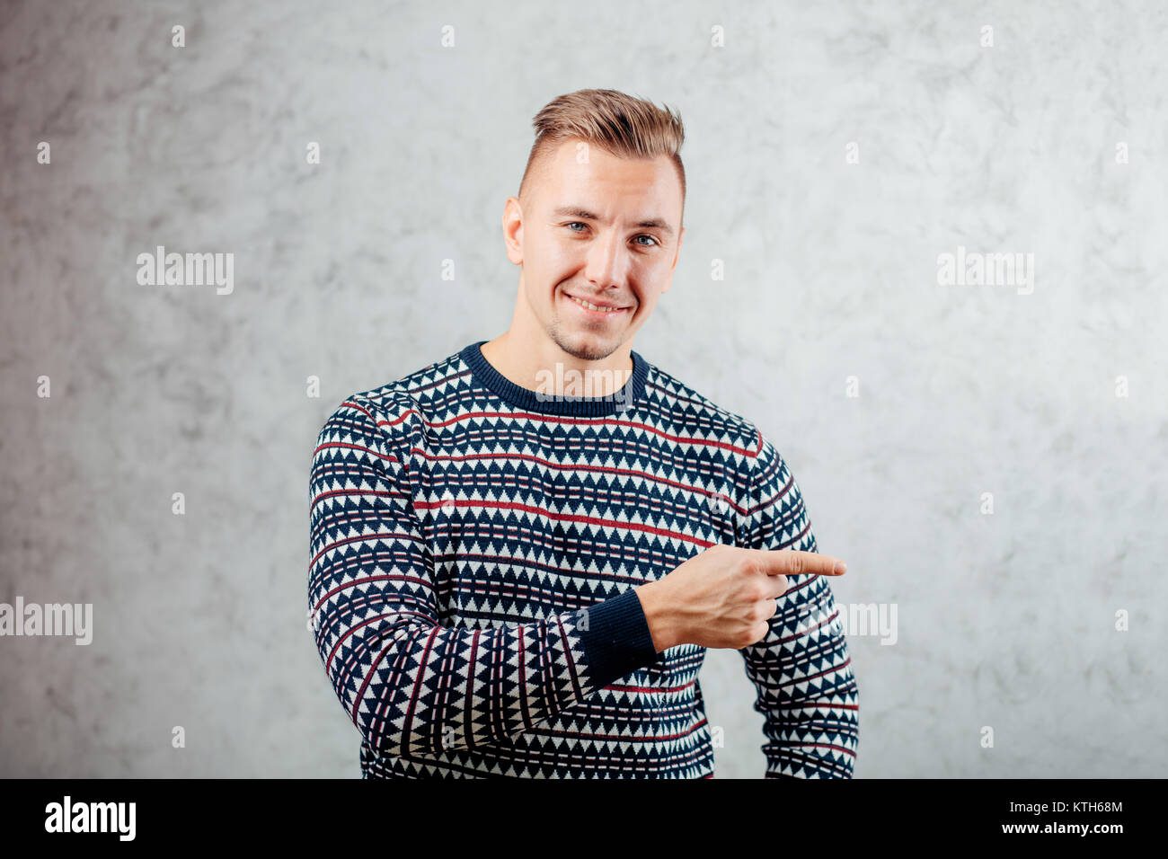 young man pointing directions on textured concrete wall background ...