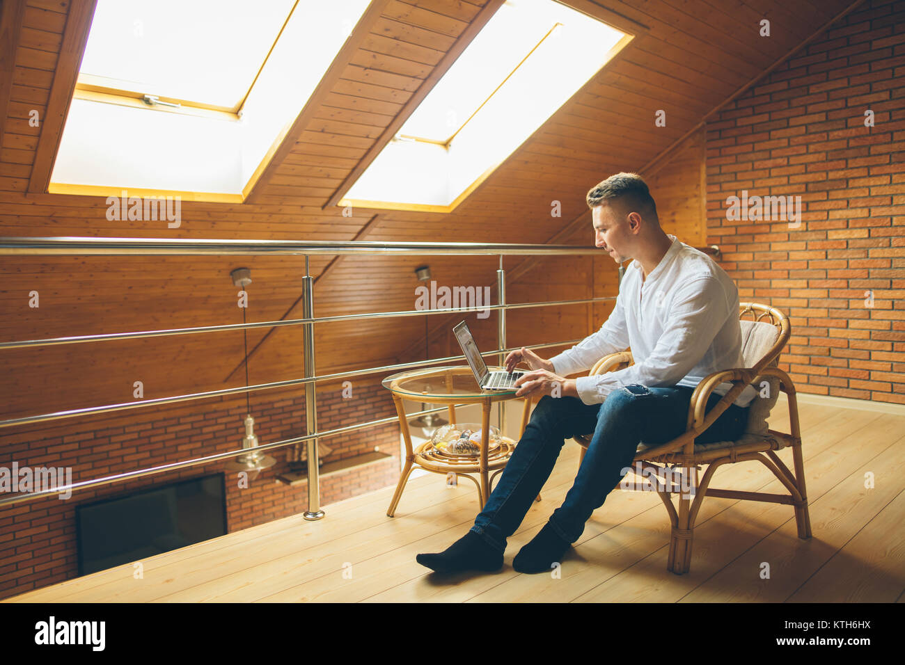 man sitting at home and working on laptop. male working from loft home ...
