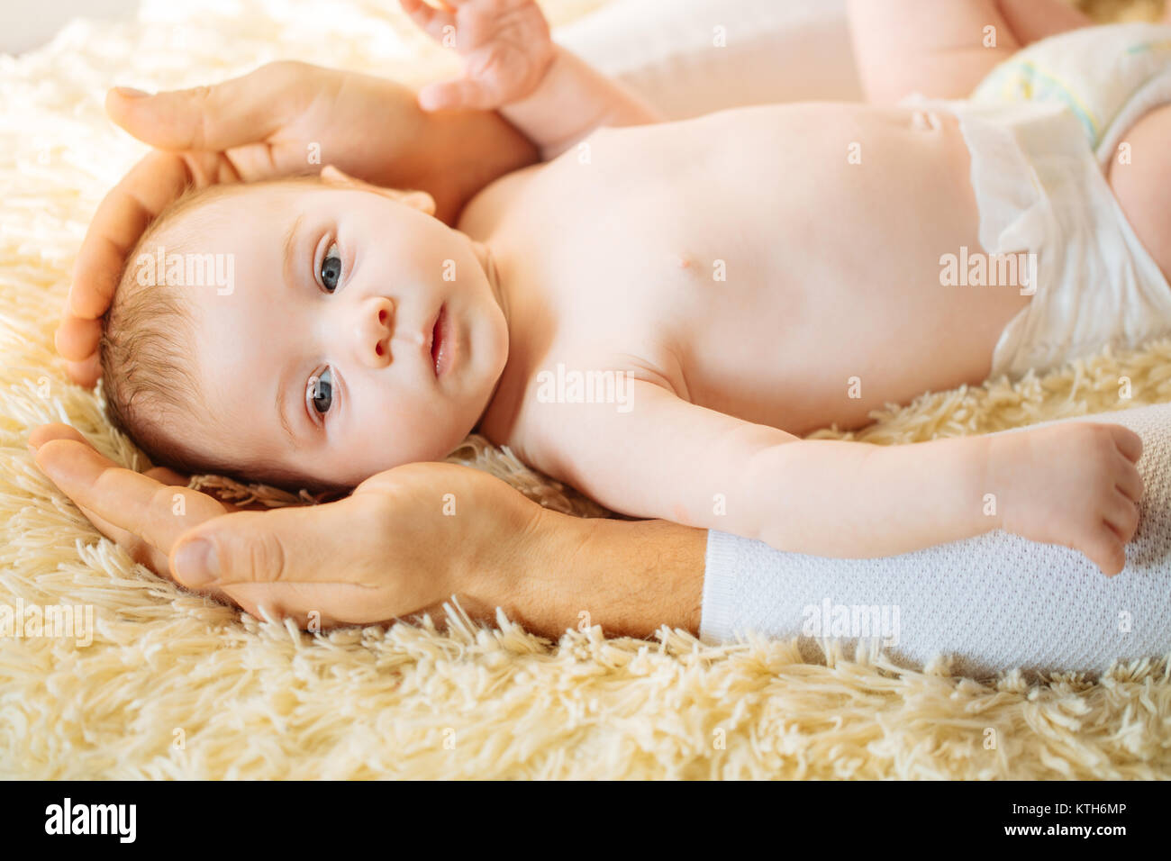 newborn baby lying down smiling looking at camera while father holding his head Stock Photo - Alamy