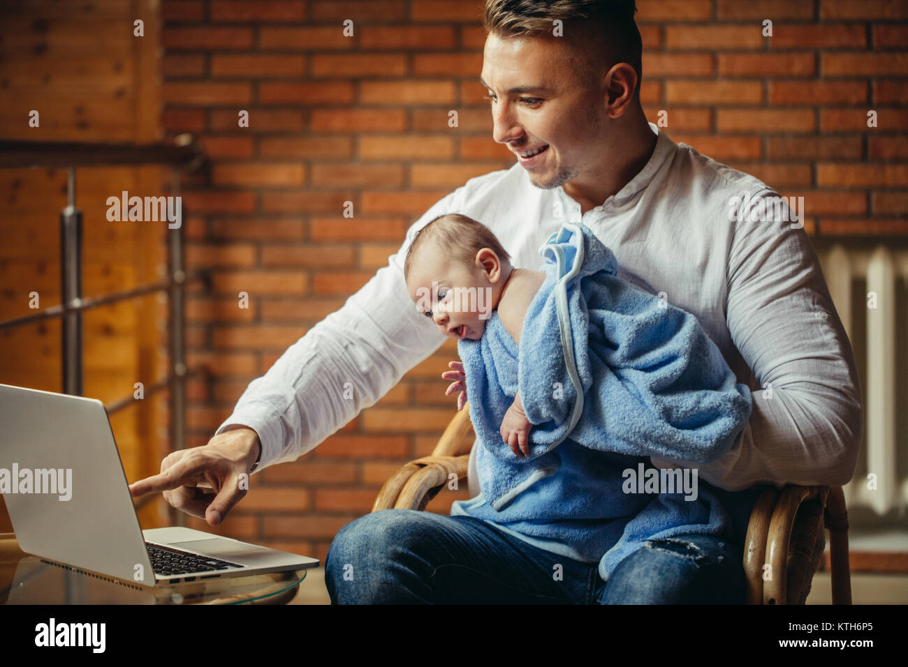 Father With Newborn Baby Working From Home Using Laptop Stock Photo - Alamy
