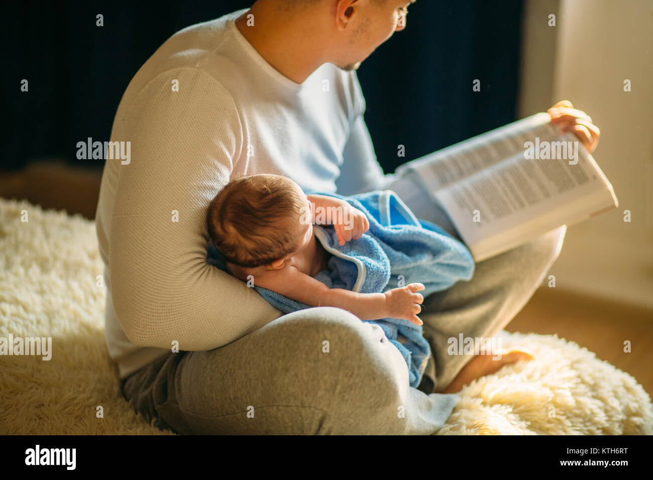 Young father and reading book to little baby Stock Photo - Alamy