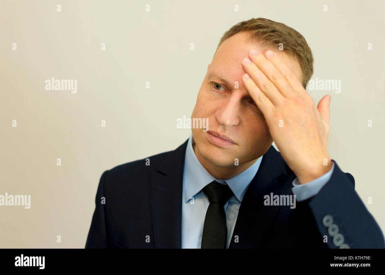 Handsome man in suit posing and looking with hand on forehead Stock ...