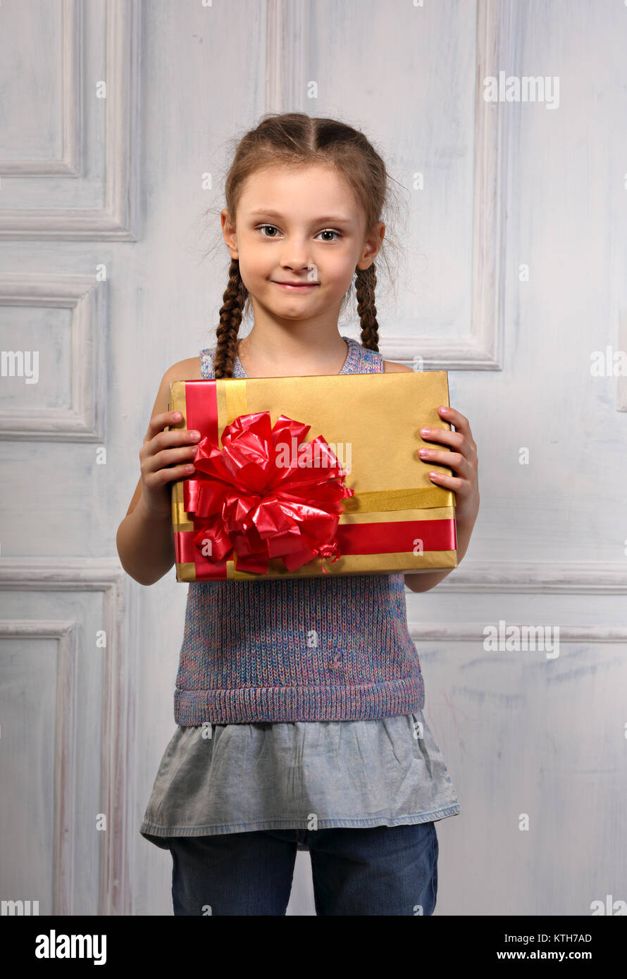 Beautiful smiling cute girl holding the gold box with gift with red bow ...