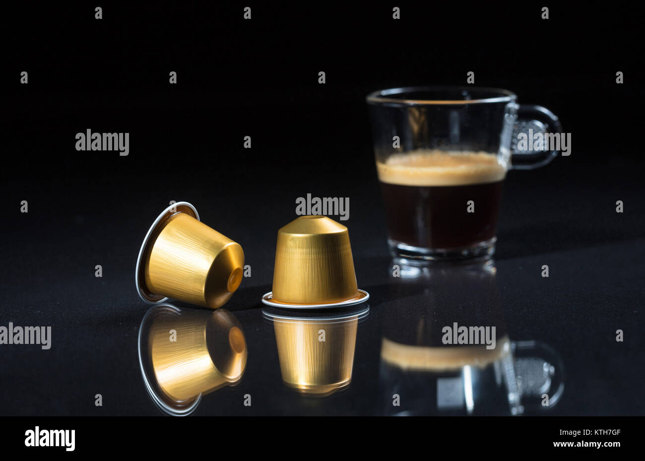 Golden espresso capsules and coffee cup on black background, Closeup ...