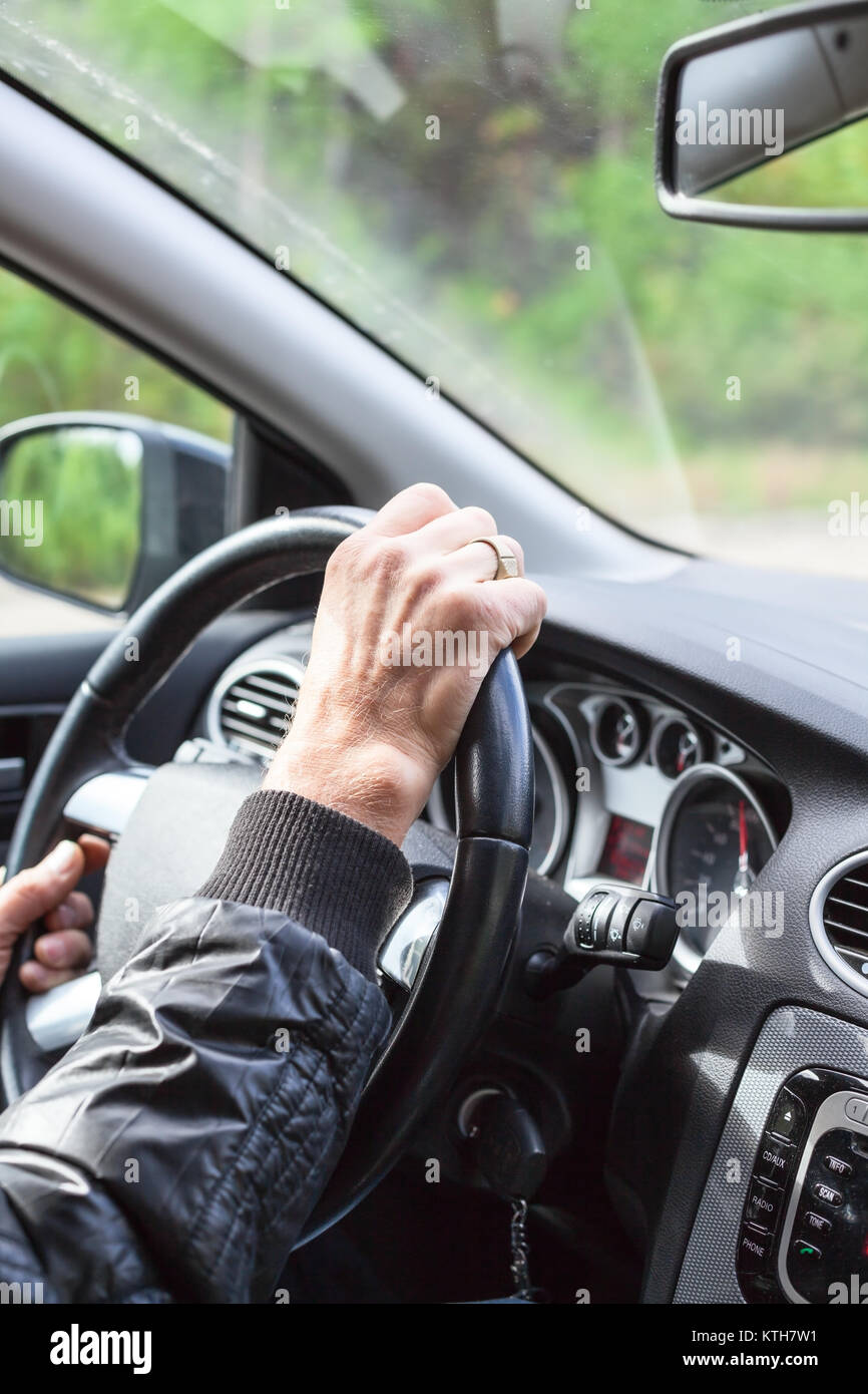 The male driver drives the car, close-up view at arms on steering wheel ...