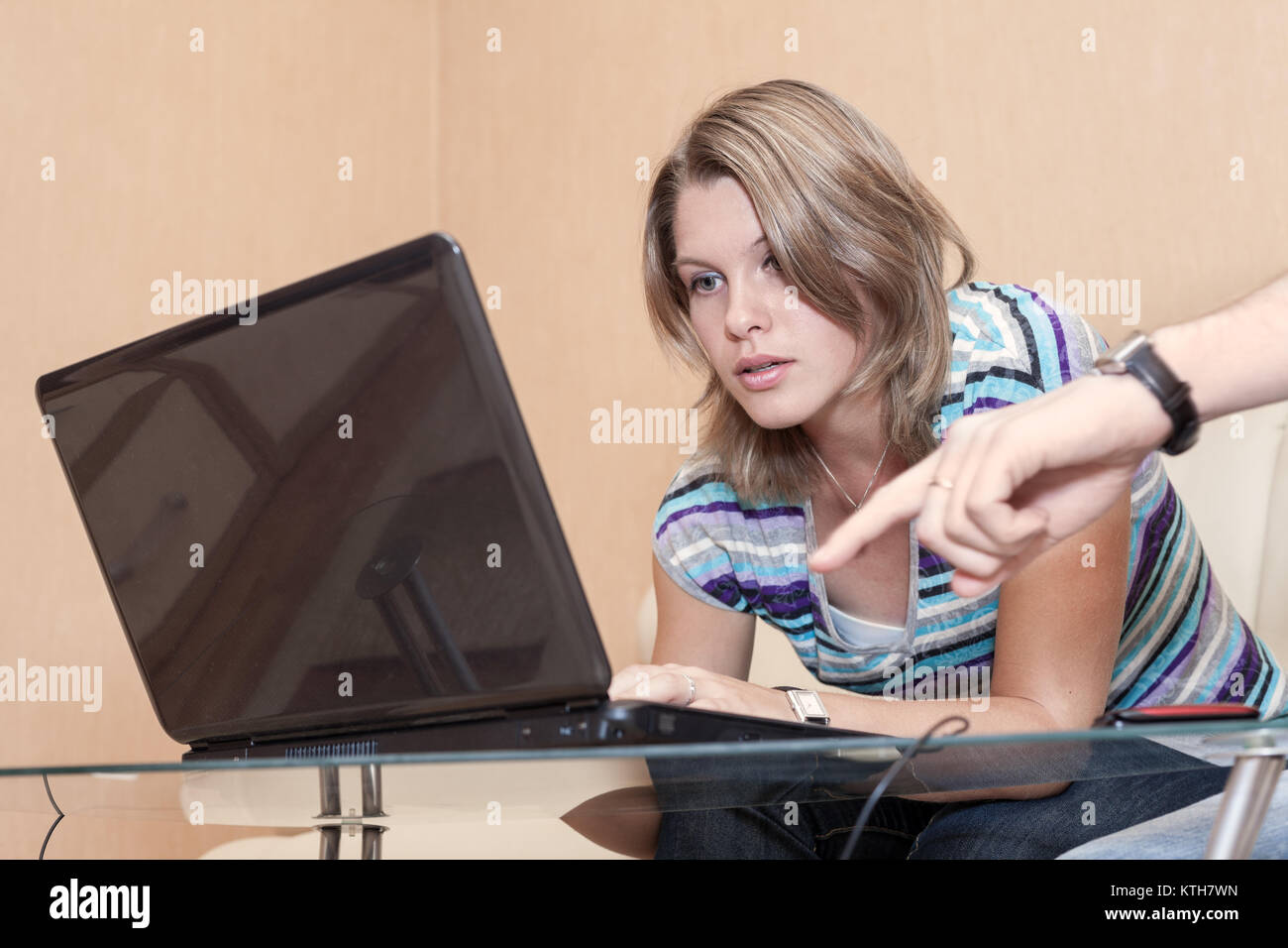 Male hand pointing laptop screen and young woman follows the gesture ...