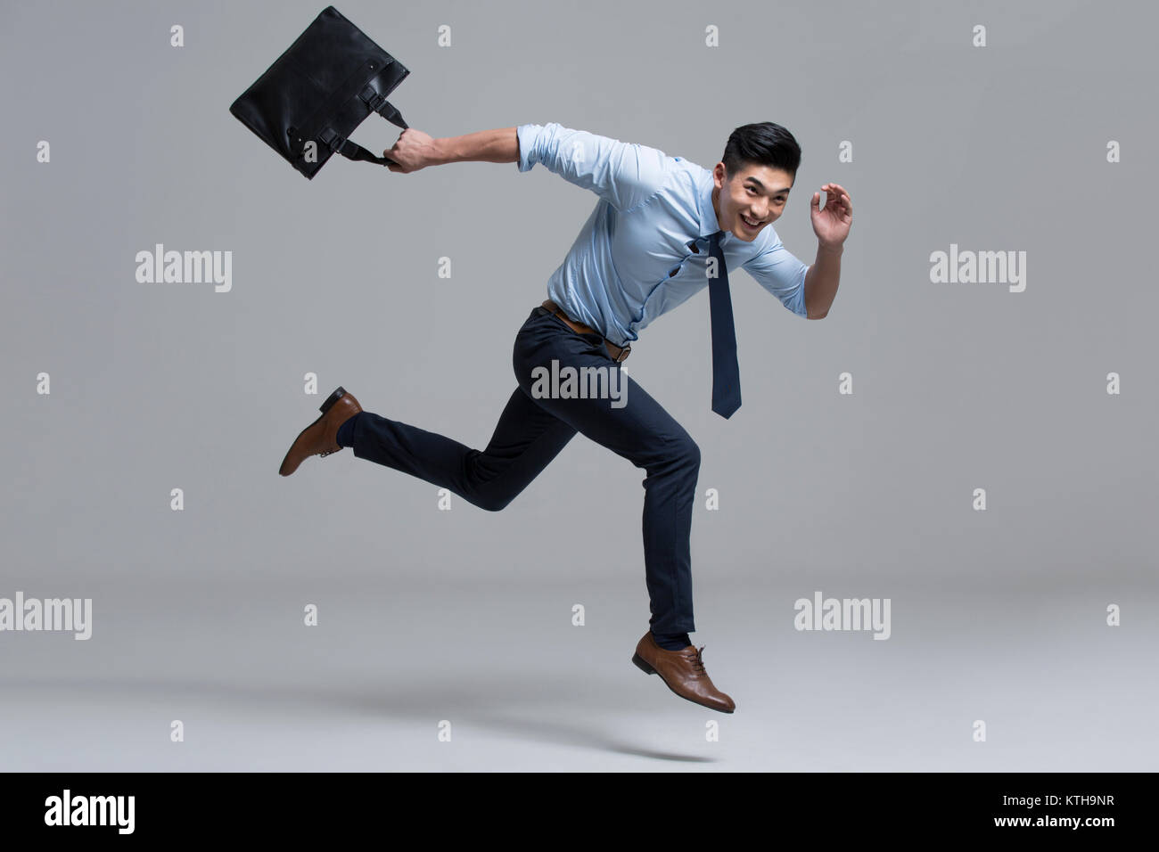 Cheerful young businessman running with briefcase Stock Photo - Alamy