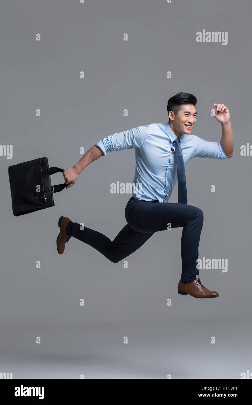 Cheerful young businessman running with briefcase Stock Photo - Alamy