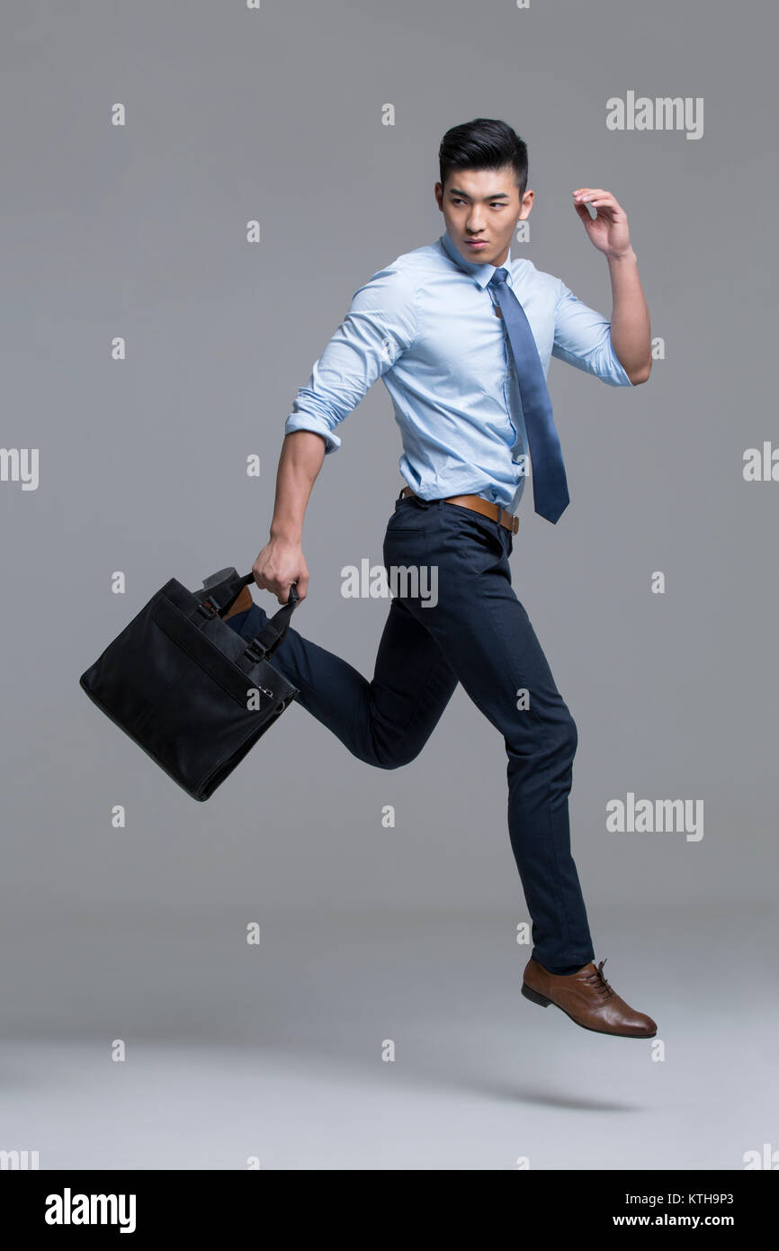 Cheerful young businessman running with briefcase Stock Photo - Alamy