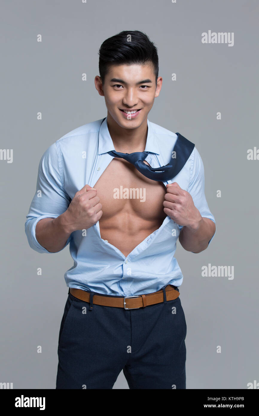 Cheerful young businessman showing muscles Stock Photo - Alamy