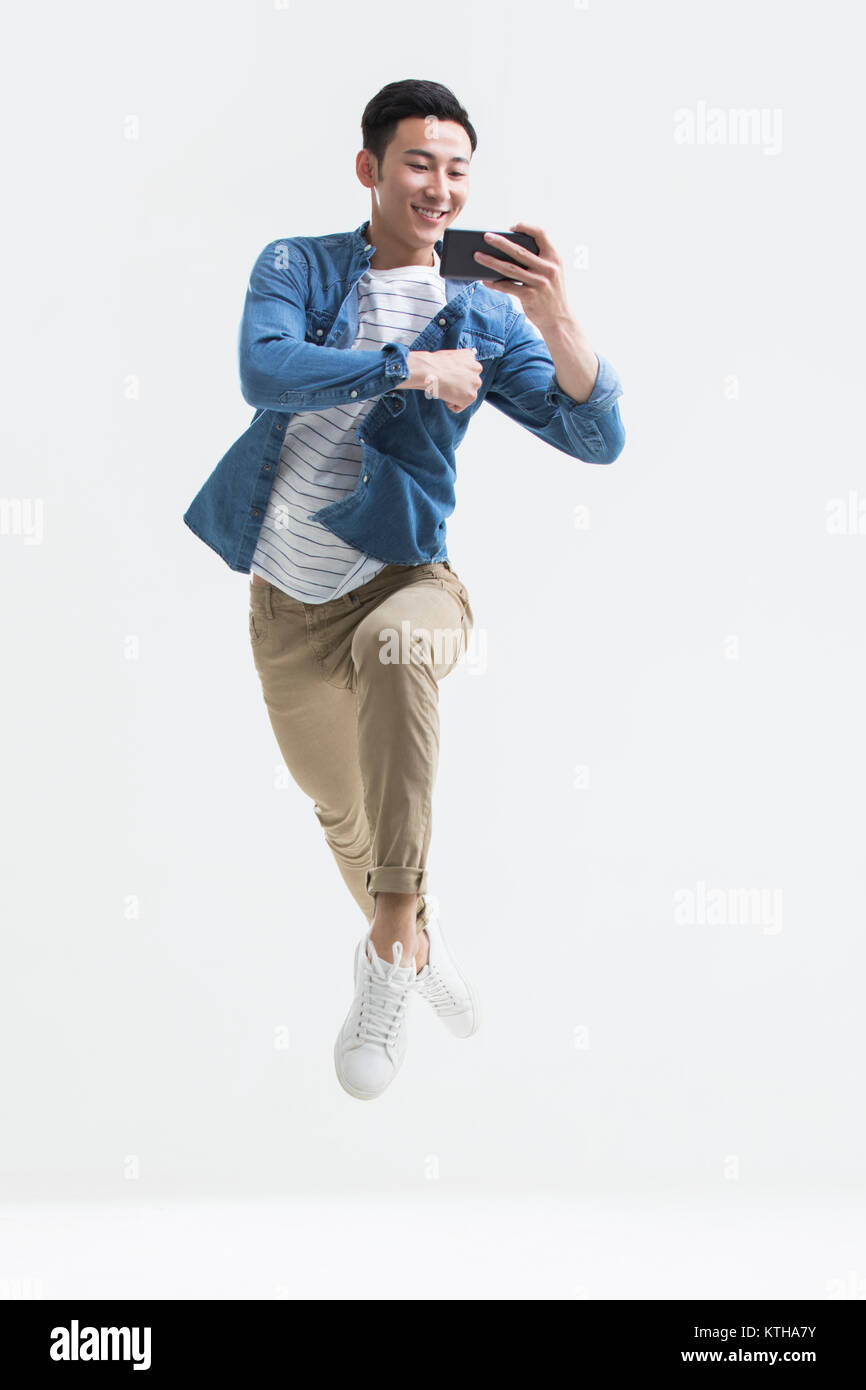 Young man jumping with a smart phone Stock Photo - Alamy