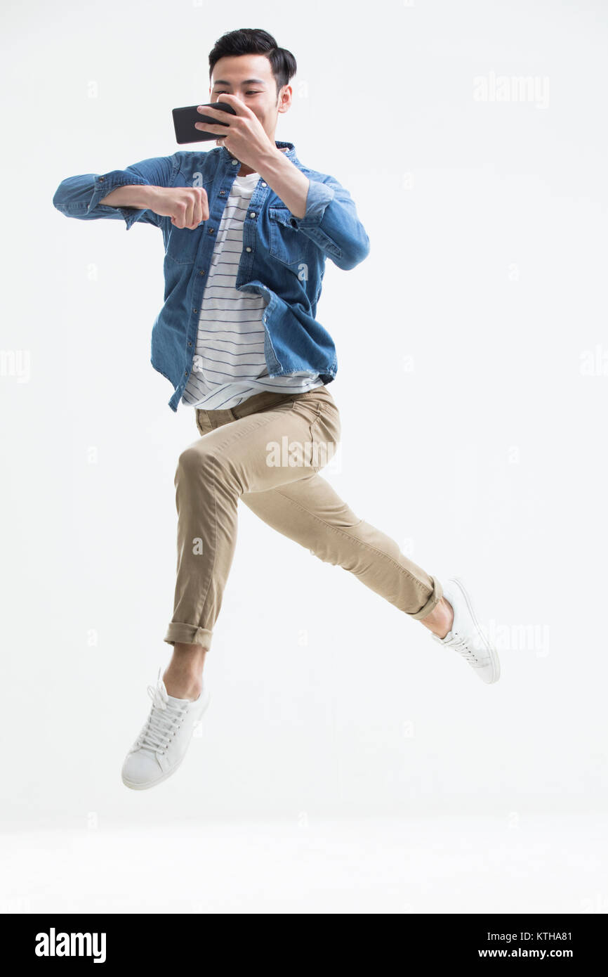 Young man jumping with a smart phone Stock Photo - Alamy