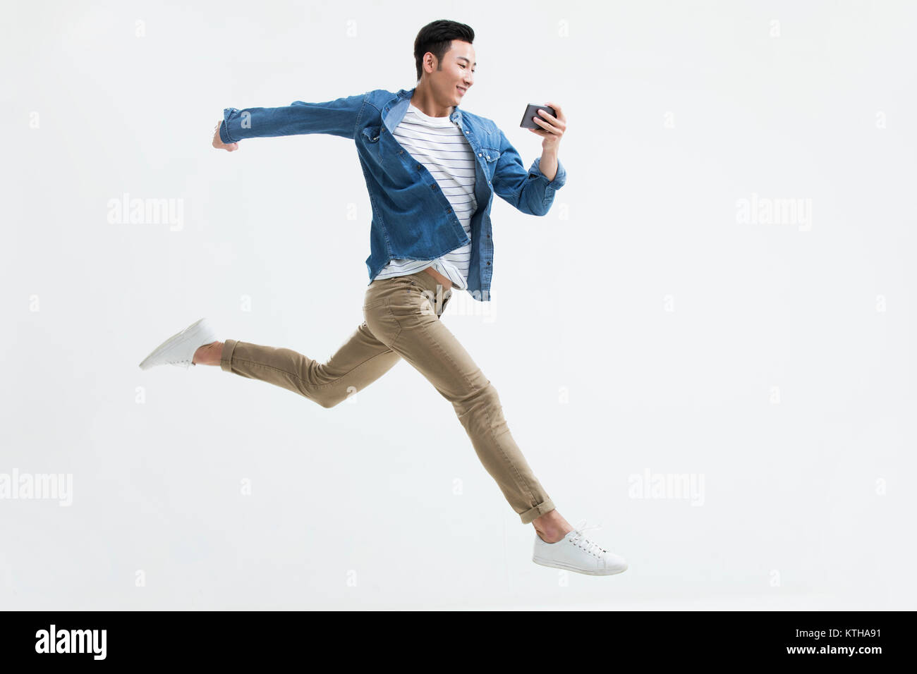 Young man jumping with a smart phone Stock Photo - Alamy