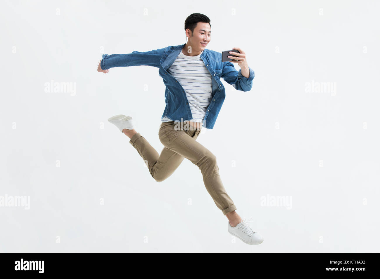 Young man jumping with a smart phone Stock Photo - Alamy