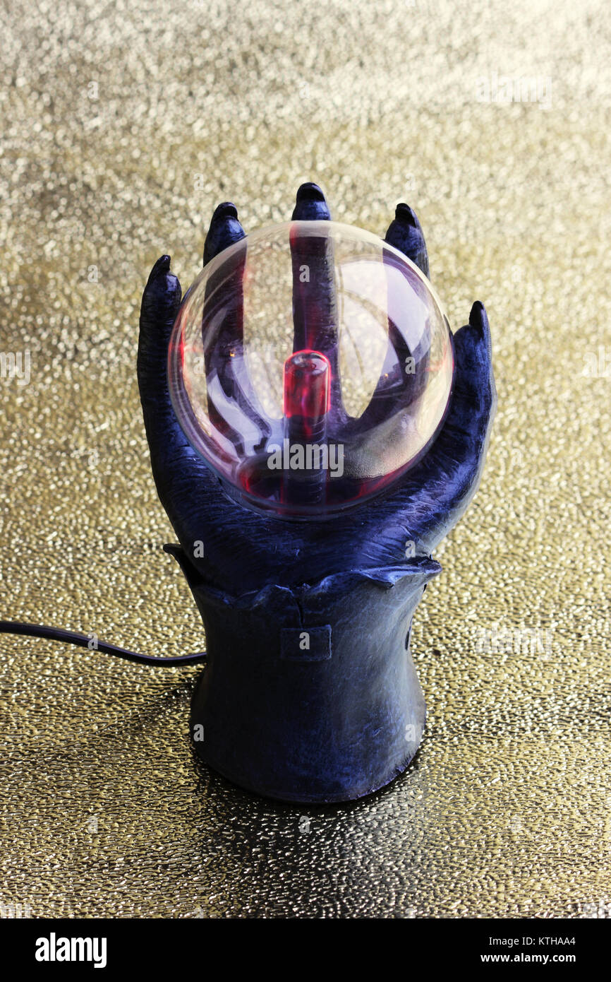 Plasma lamp ball in a plastic hand on a gold background Stock Photo - Alamy