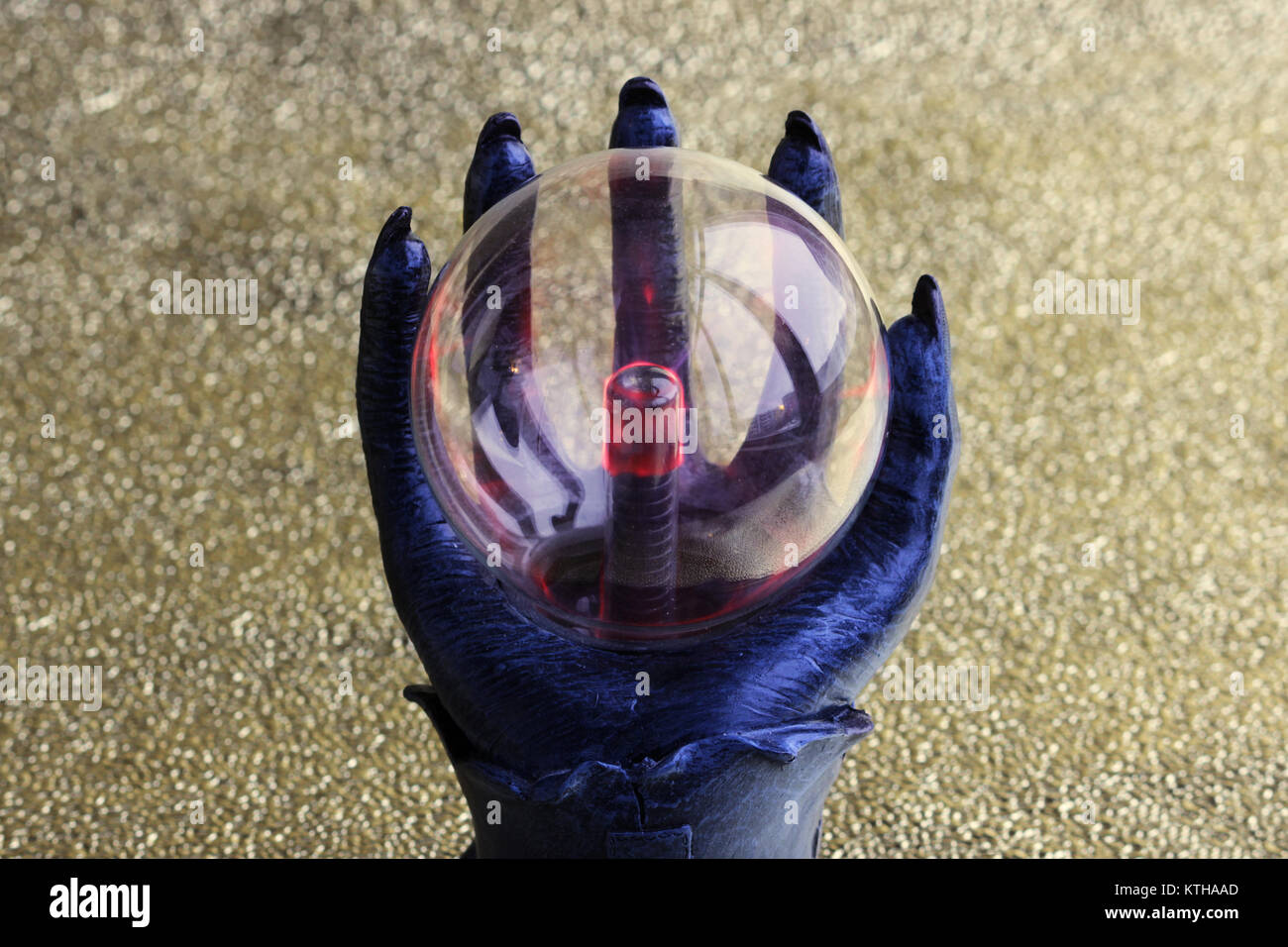 Plasma lamp ball in a plastic hand on a gold background Stock Photo - Alamy