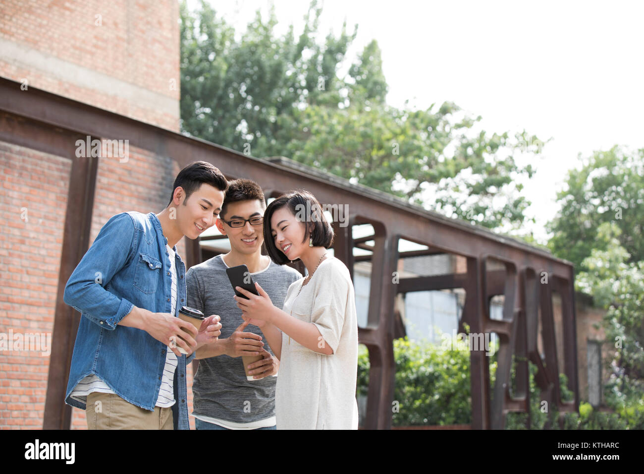 Cheerful young friends using smart phone Stock Photo - Alamy