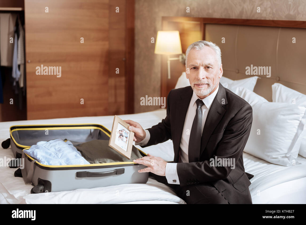 Glad senior man packing his photo to suitcase Stock Photo - Alamy