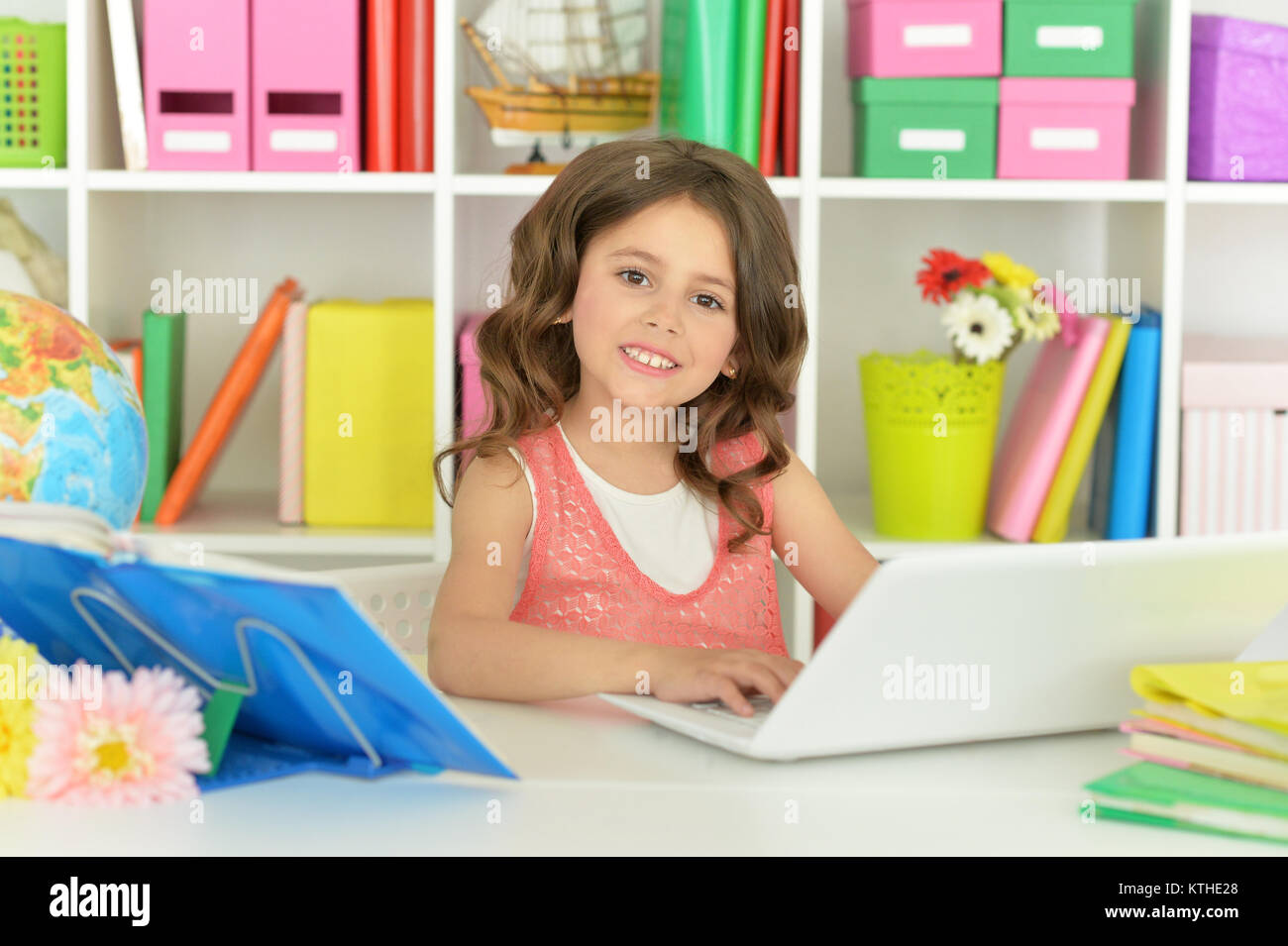 Adorable little girl sitting at table with laptop Stock Photo - Alamy