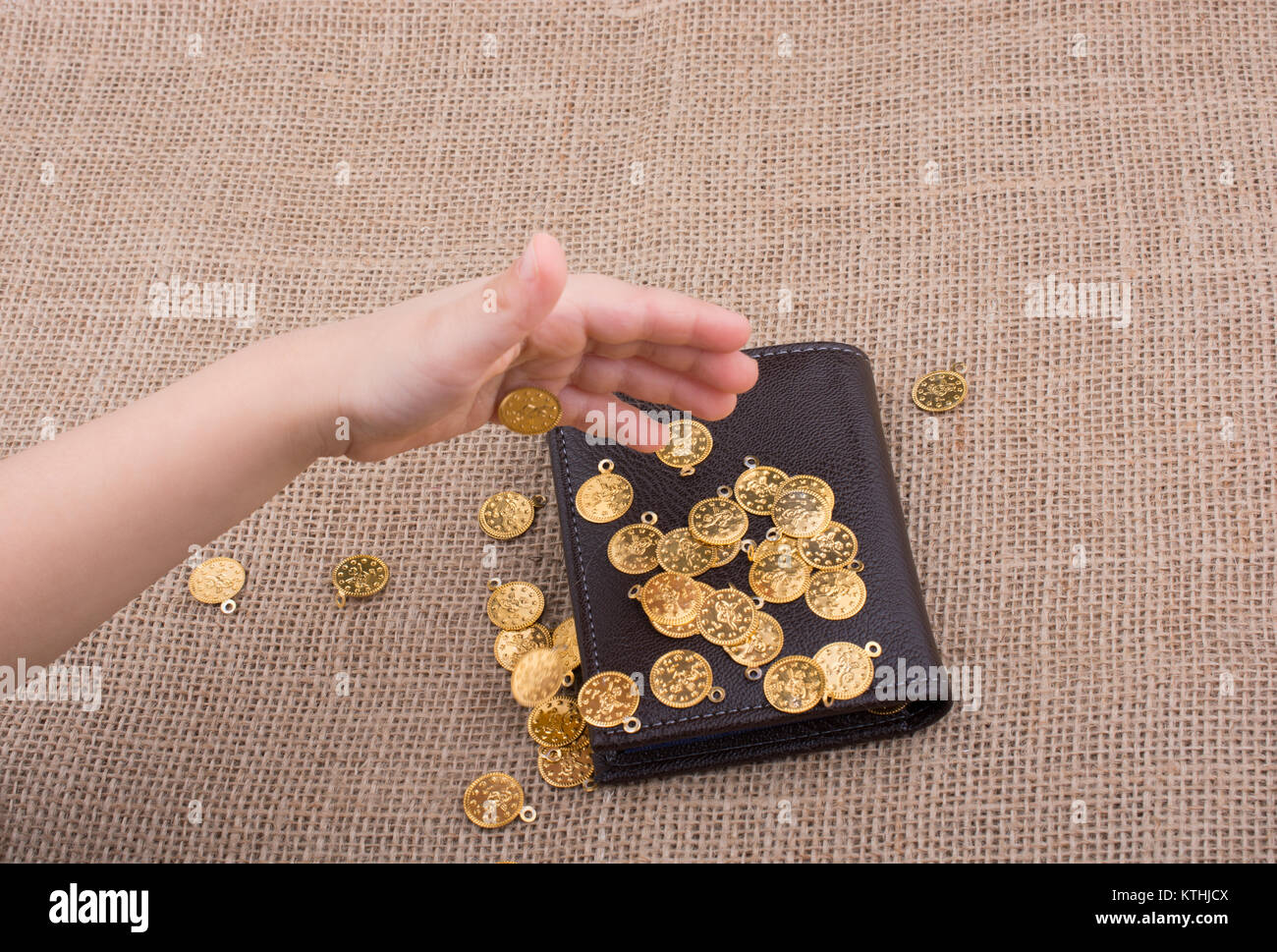 Wallet and plenty of fake gold coins in hnad Stock Photo - Alamy