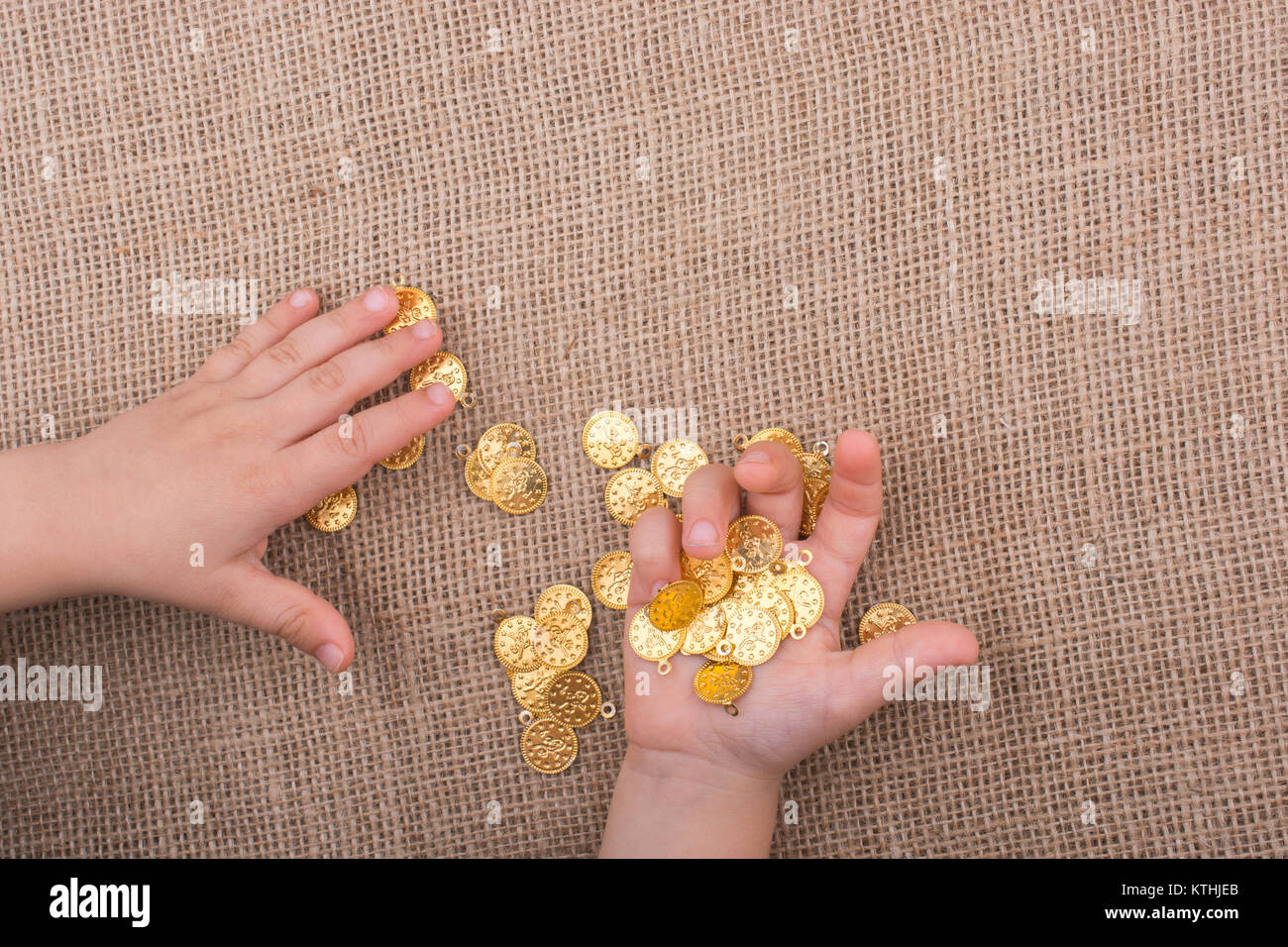 Plenty of fake gold coins in hand on canvas Stock Photo - Alamy
