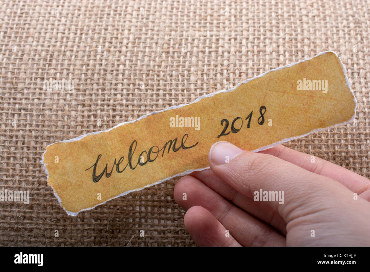 Welcome 2018 wording written on a torn paper in hand Stock Photo - Alamy